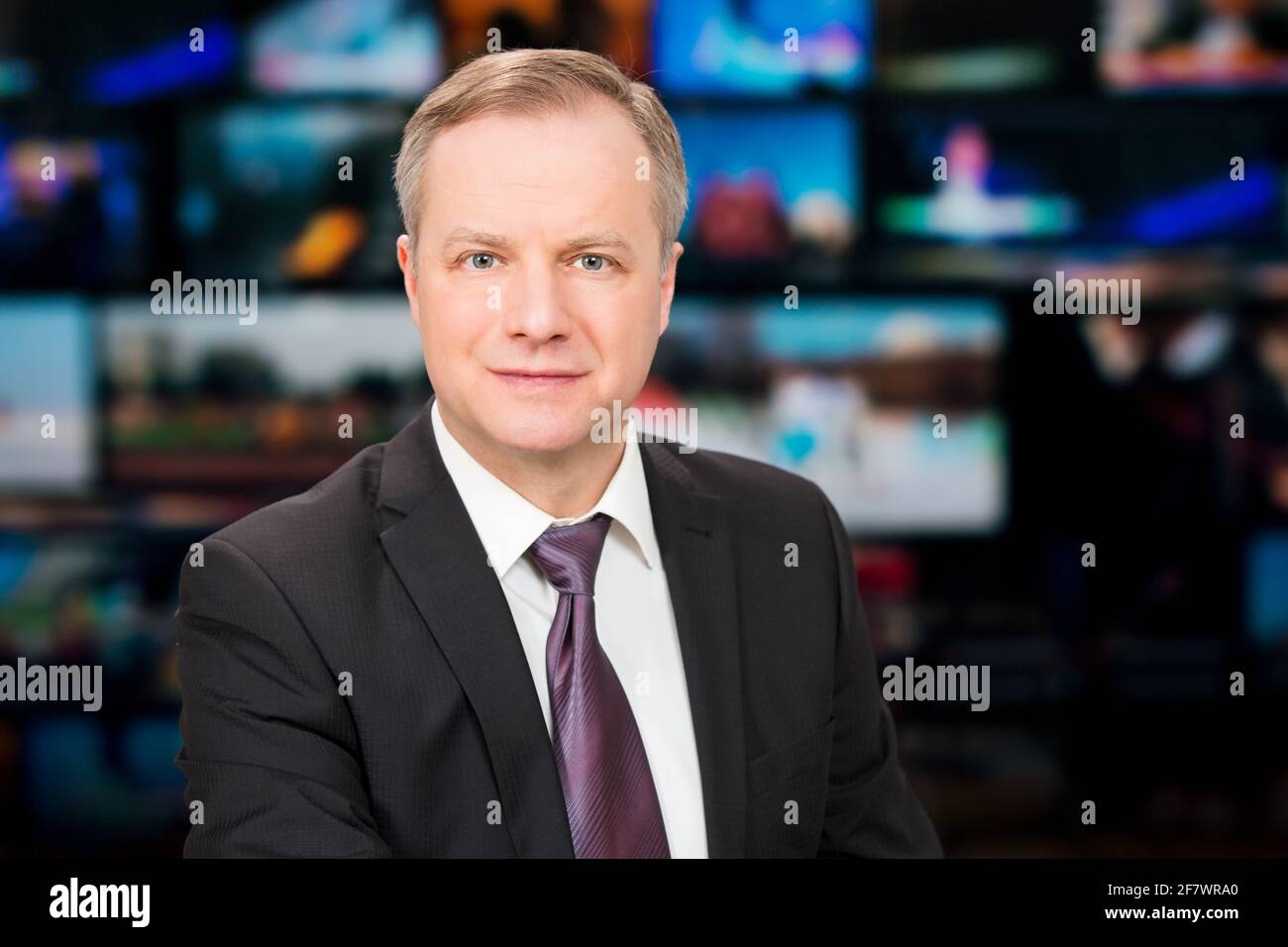 An anchorman reporting live breaking news sitting in Tv studio ...