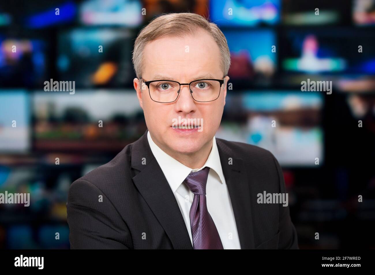 An anchorman reporting live breaking news sitting in Tv studio ...