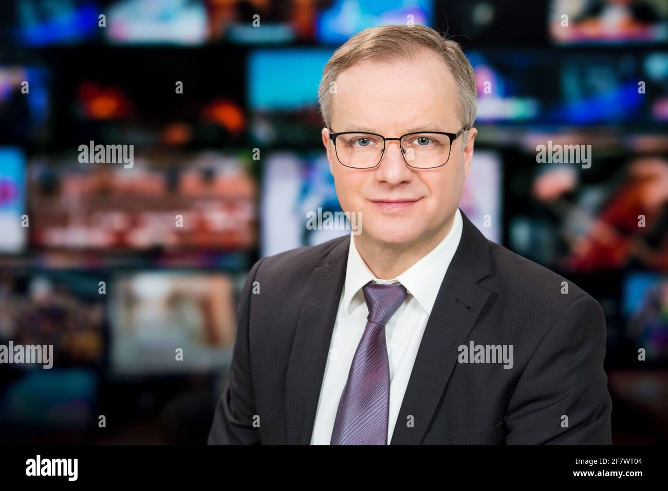 An anchorman reporting live breaking news sitting in Tv studio ...