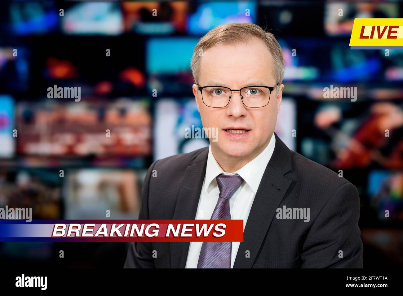 An anchorman reporting live breaking news sitting in Tv studio ...