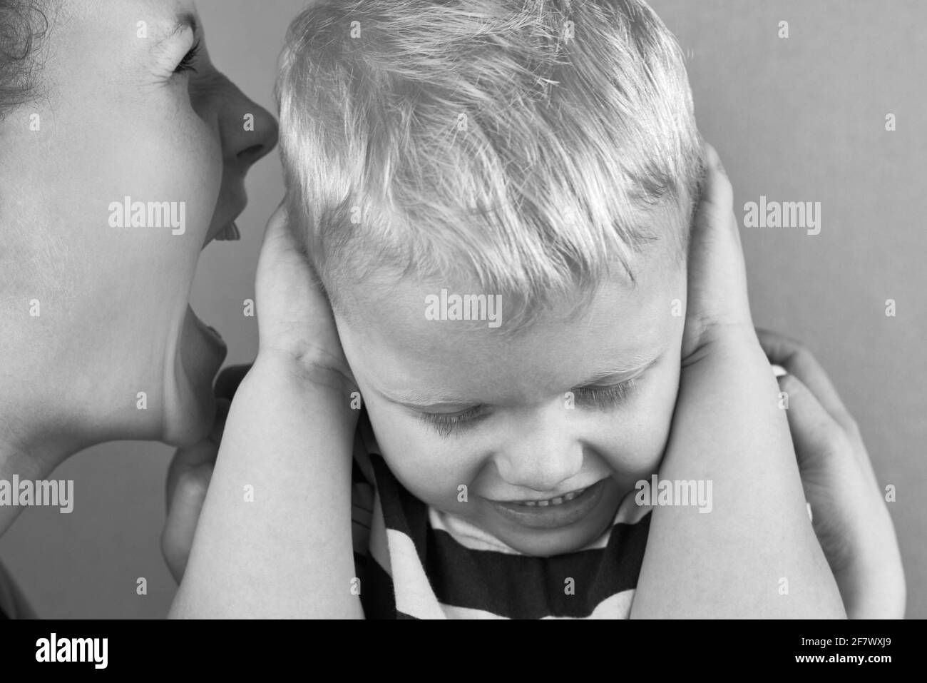 Little boy covers his ears with his hands while angry mom yells at him ...