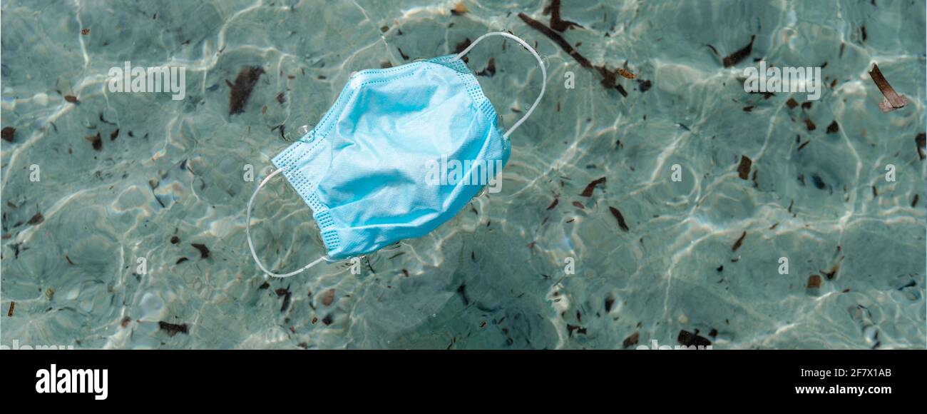 Surgical face mask floating on clear waters. Environmental damage ...