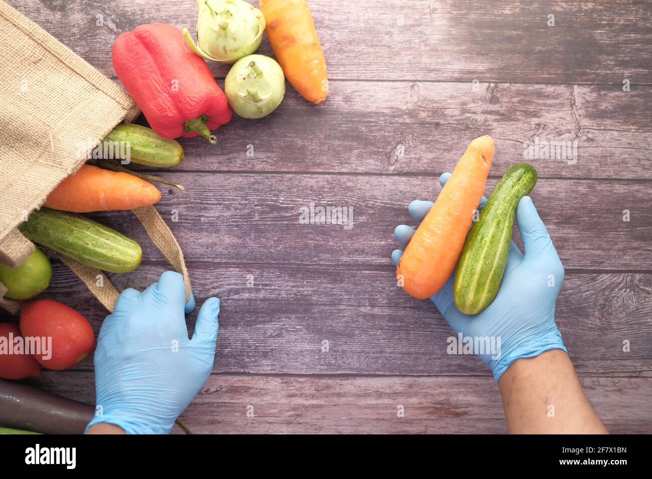 hand in gloves taking vegetable out from a reusable bag vegetables top ...