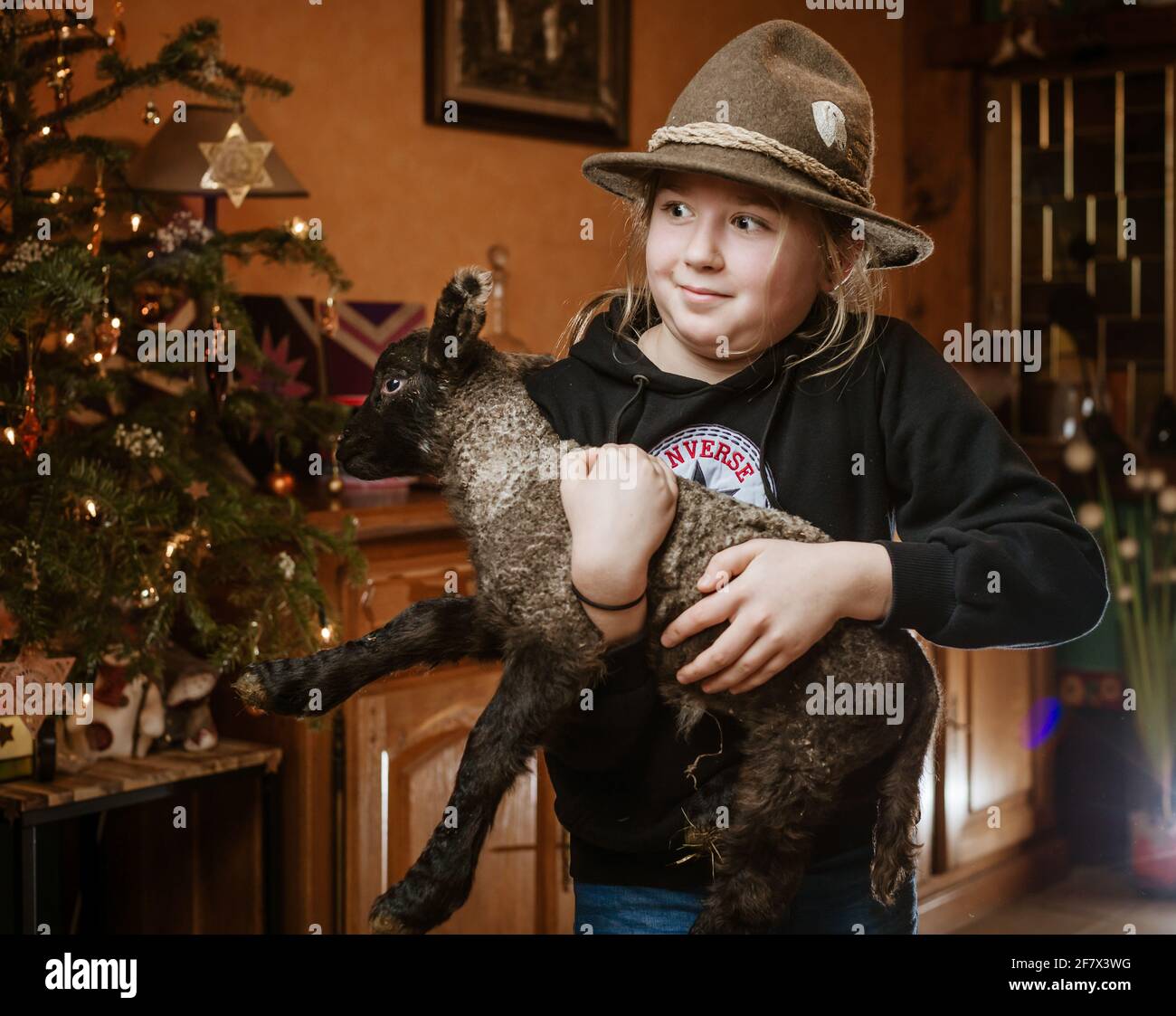 A girl in a shepherd's hat with a young newborn lamb in her arms Stock ...