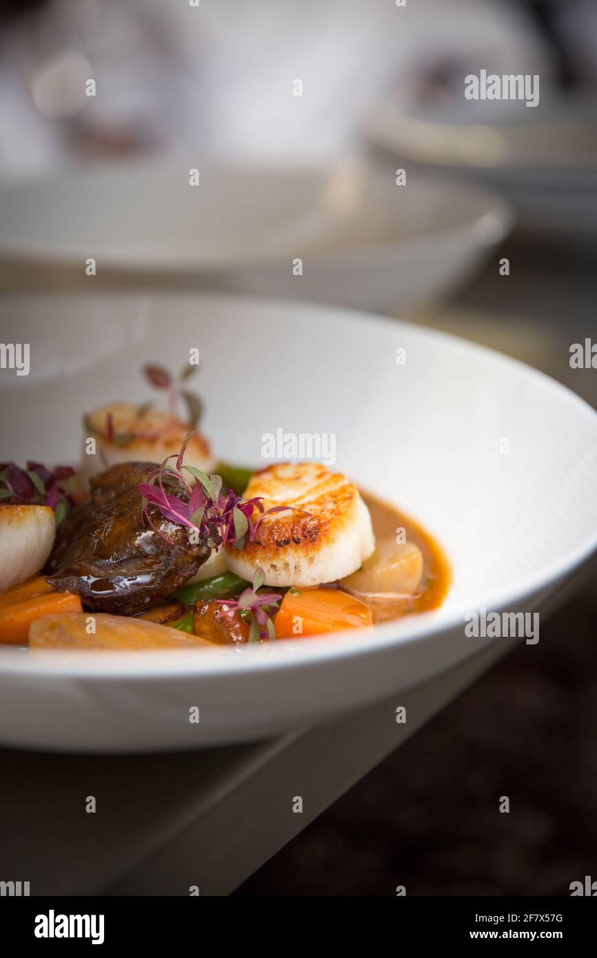 a fancy fine dining dish bowl sitting on edge of stainless steel ...