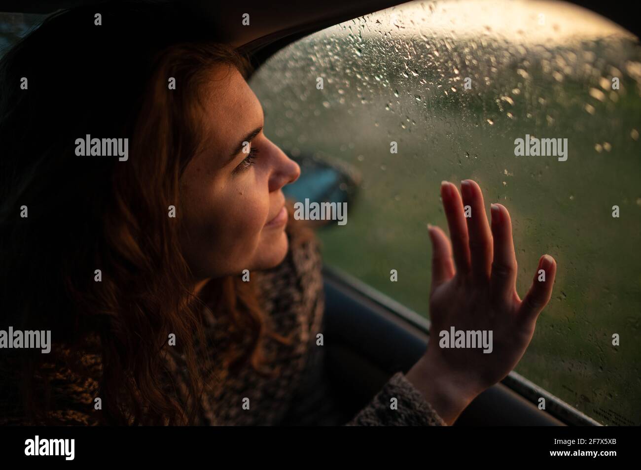 Side view Portrait of young woman inside car while raining. Smiley face ...