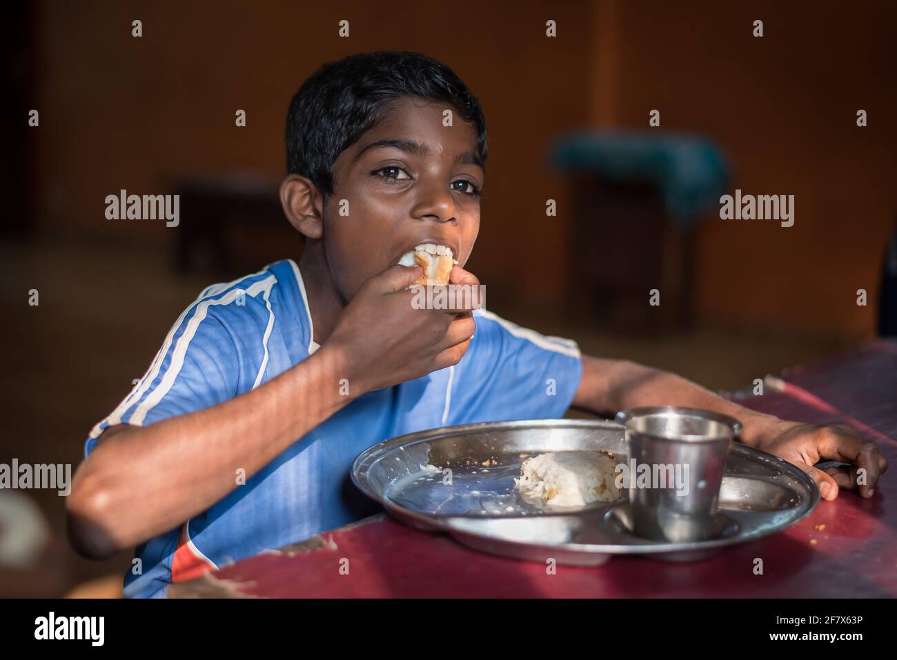 Varanasi, India. 10-14-2019. A hungry student boy is finishing his ...