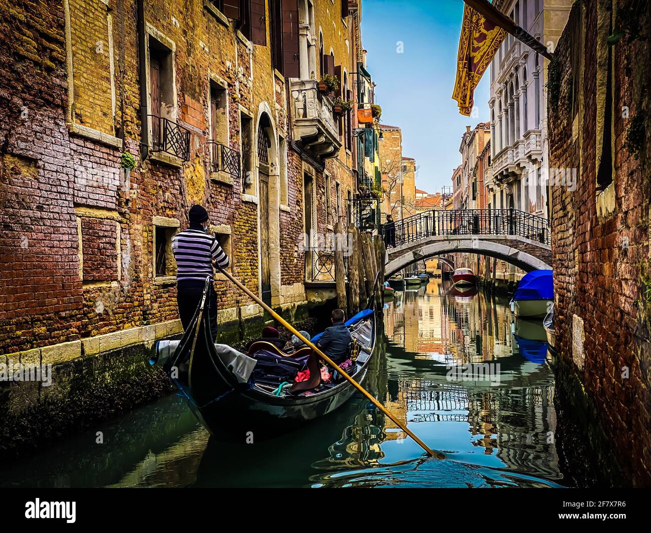 Gondolier seen from behind, driving a gondola with a family of tourists ...