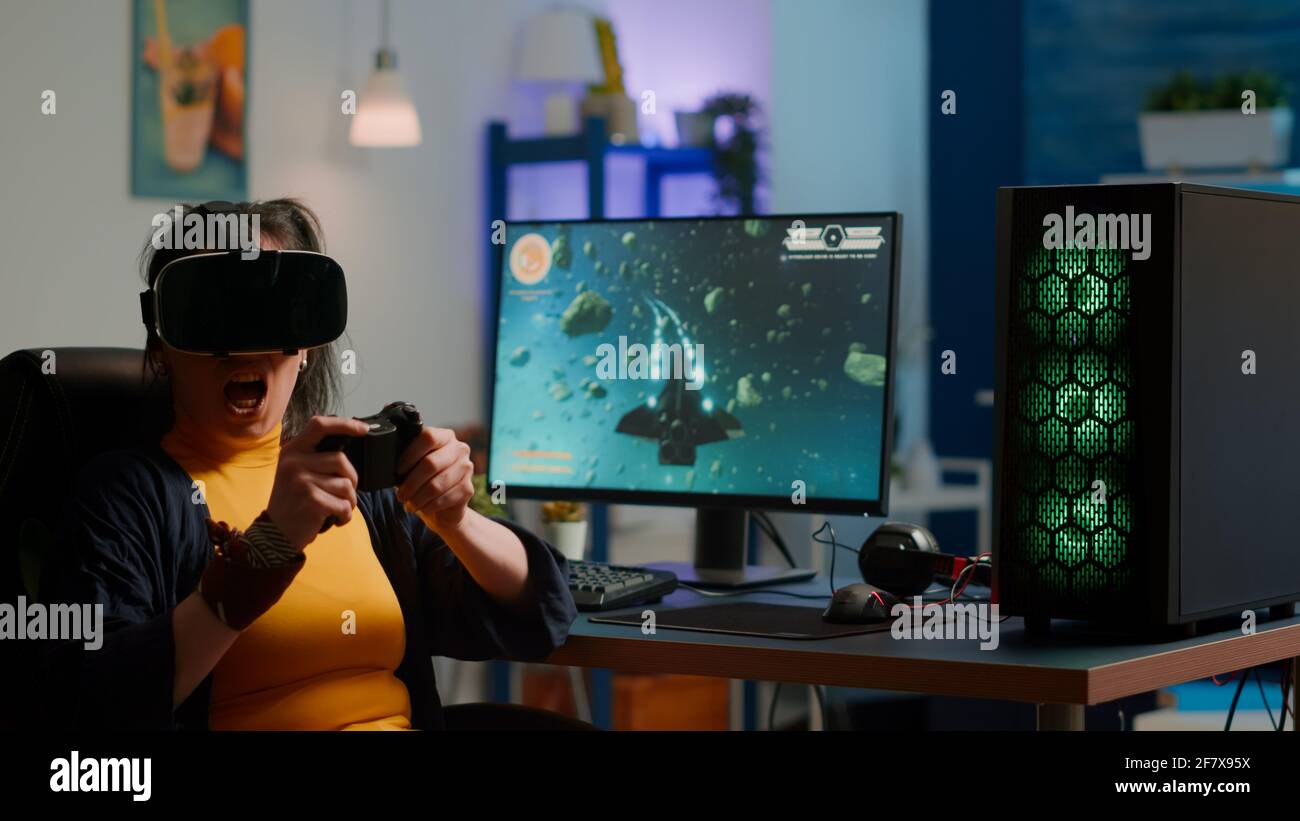 Videogame player with vr goggles raising hands after winning space ...