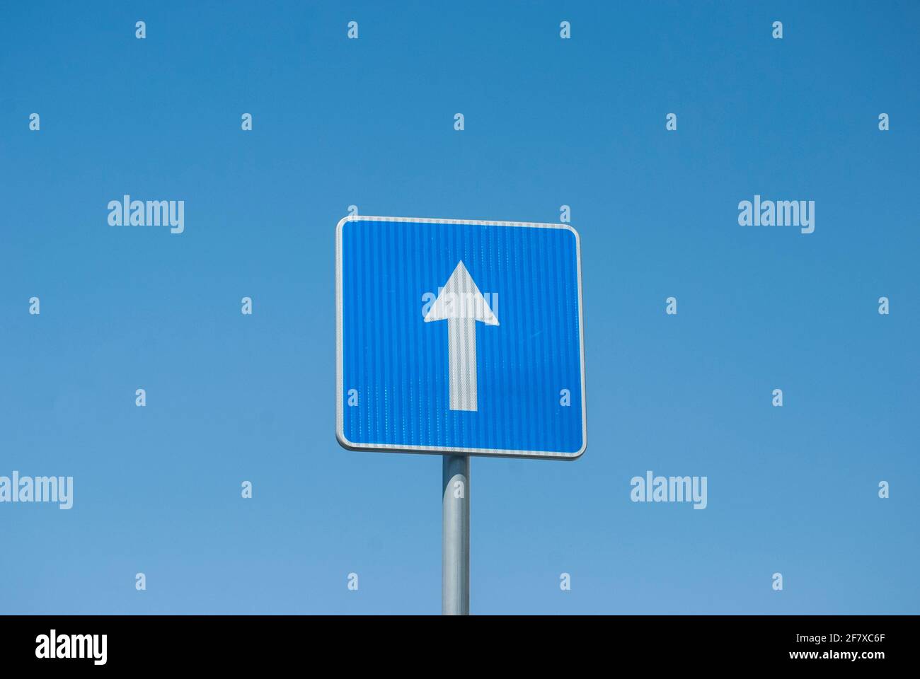 Blue rectangle one way road traffic sign closeup on blue sky background ...