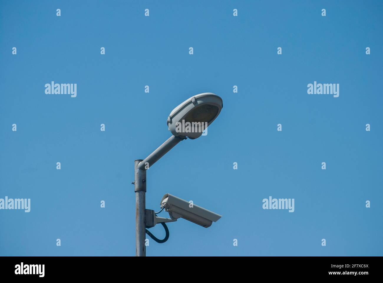 CCTV security camera on street lamp post closeup on blue sky background ...