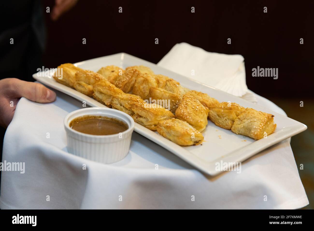 small appetizers for guests in a square white plate being held by a ...