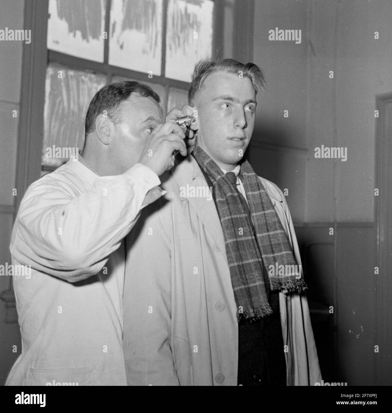 Military doctor looks at the ear of a candidate during the inspection ...