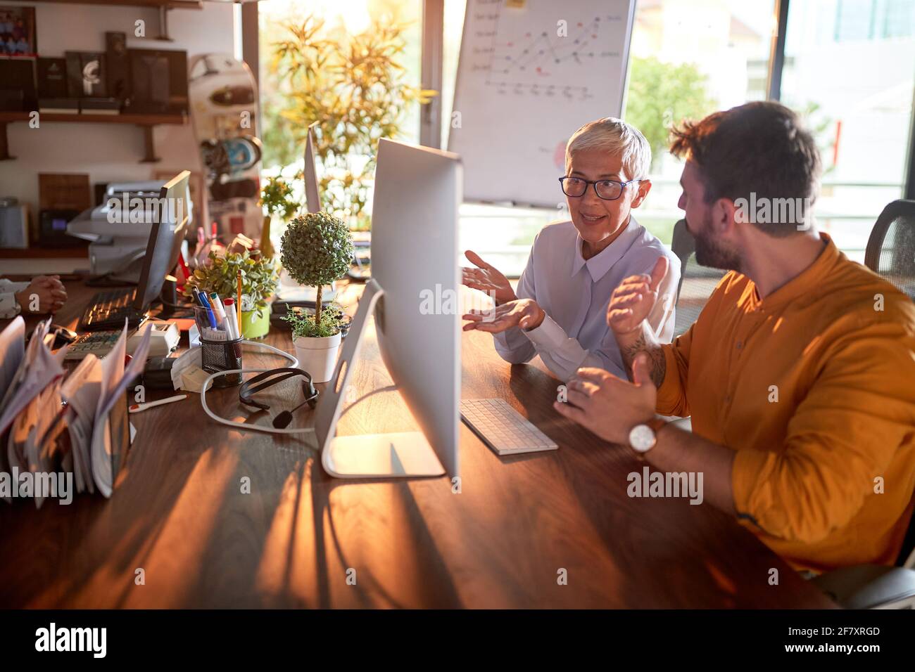 An elderly business woman is commenting a computer screen content with ...