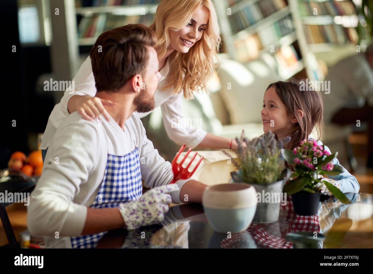 Happy parents planting flowers together with their daughter at home ...
