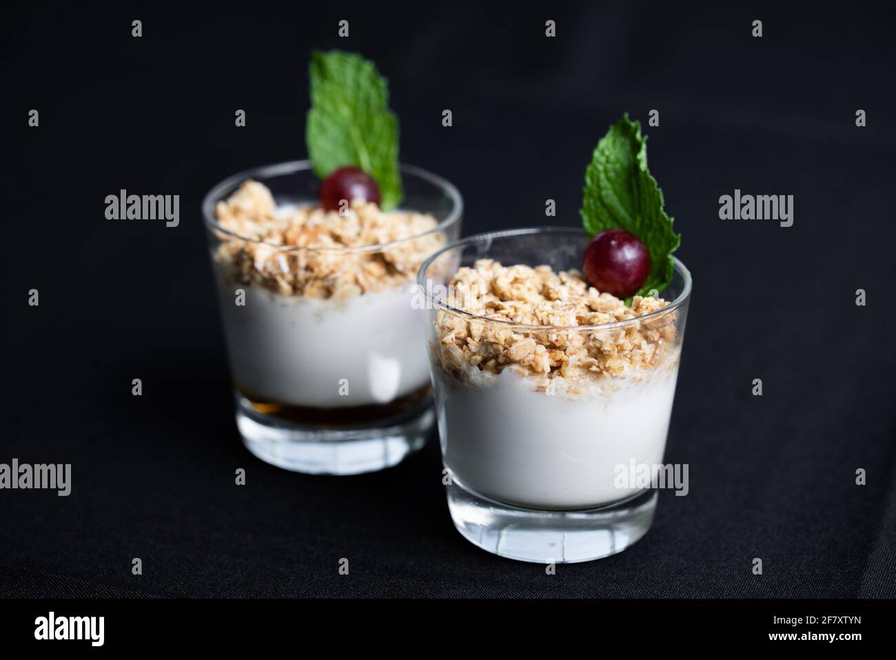 two cups of yogurt with oat and a raisin on a black background Stock ...