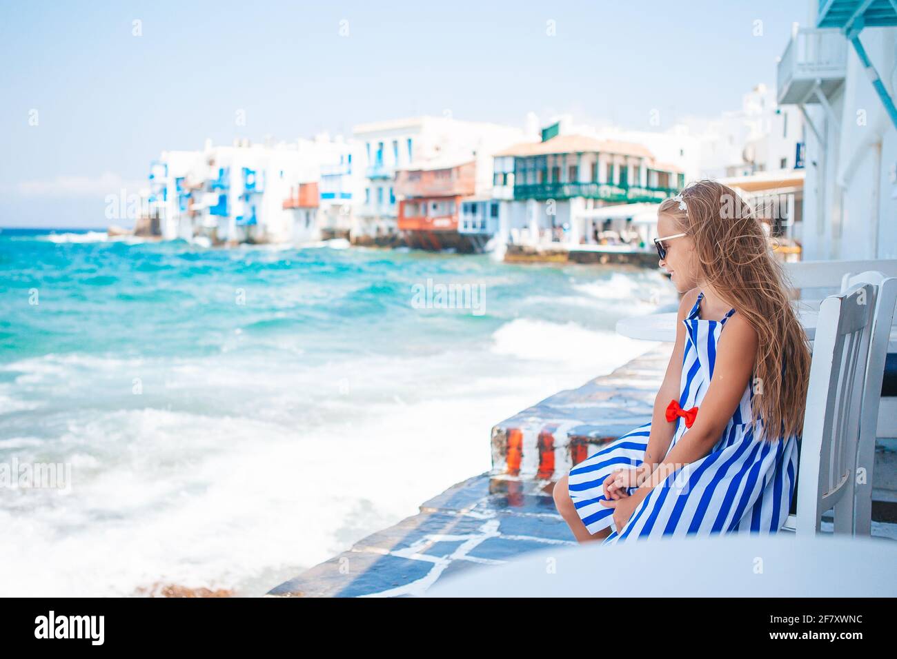 Adorable little girl at old street of typical greek traditional village ...