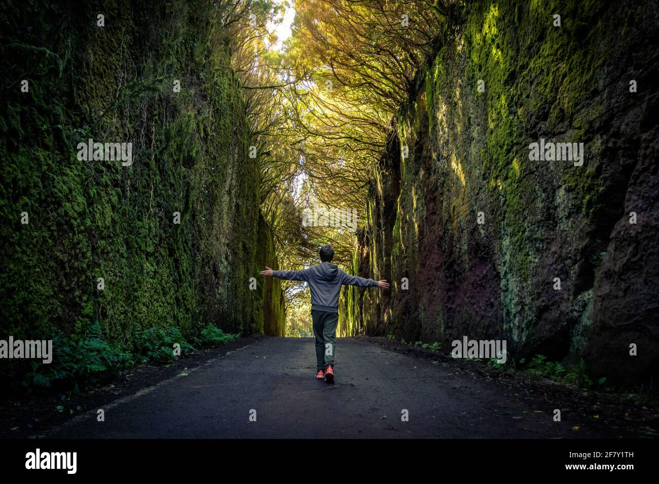 Young boy walks alone in a beautiful natural setting with arms open ...