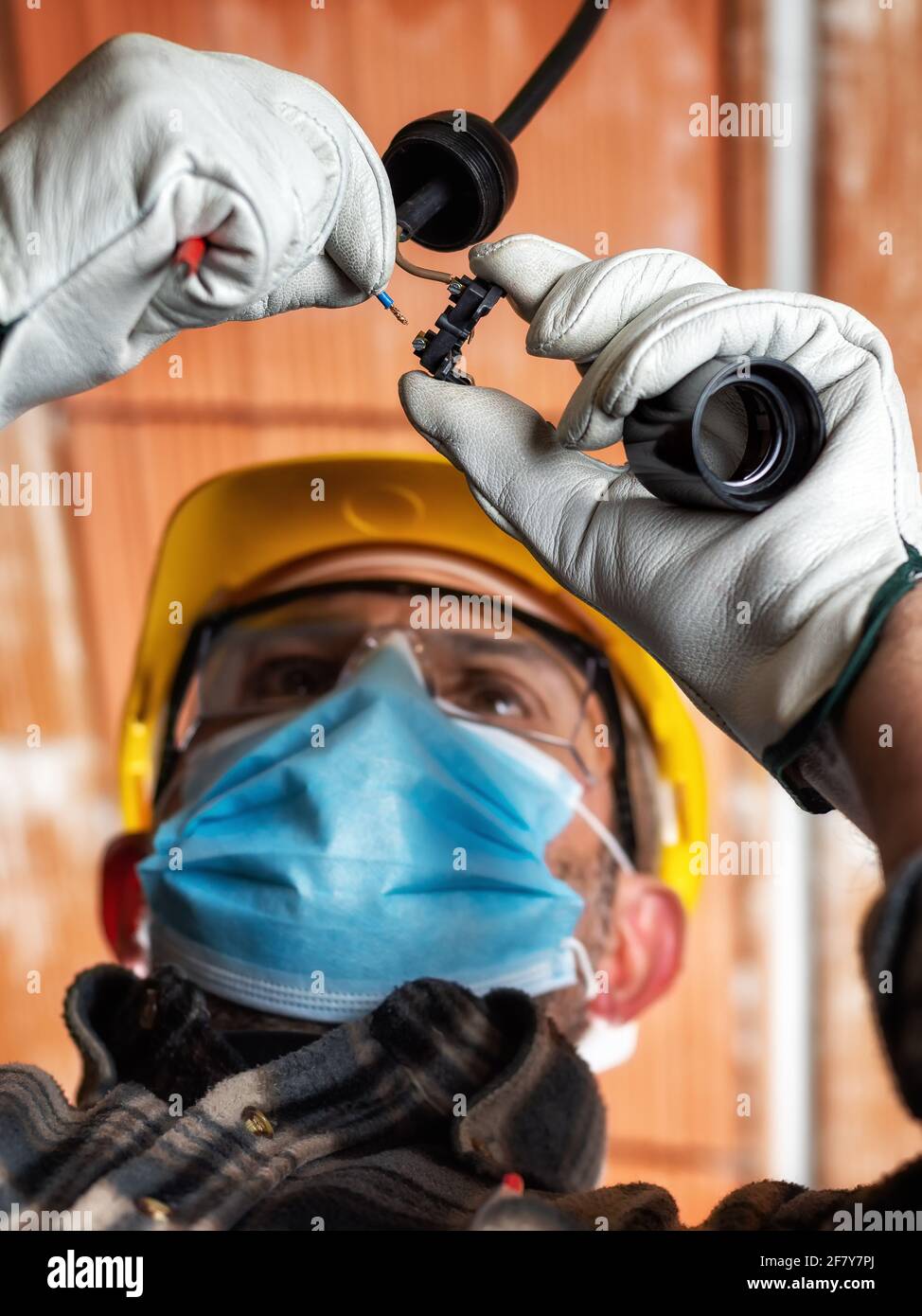 Electrician worker at work replaces the lamp holder protected by helmet ...