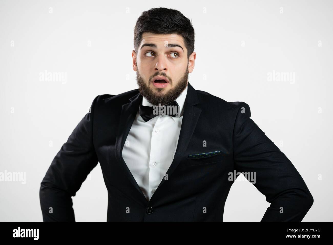 Irritated man in tuxedo sighs, rolling eyes on white background ...