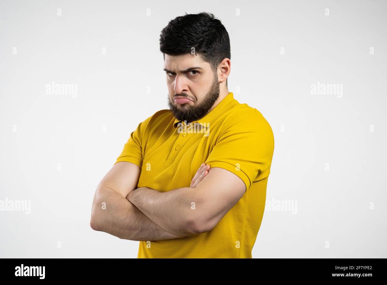 Angry offended man keeping arms crossed and staring at camera with ...