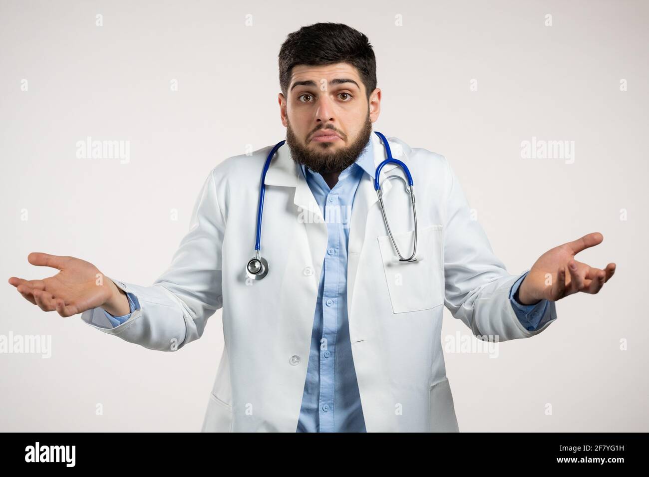 Unsure doctor man in medical coat shrugs his arms, makes gesture of I ...
