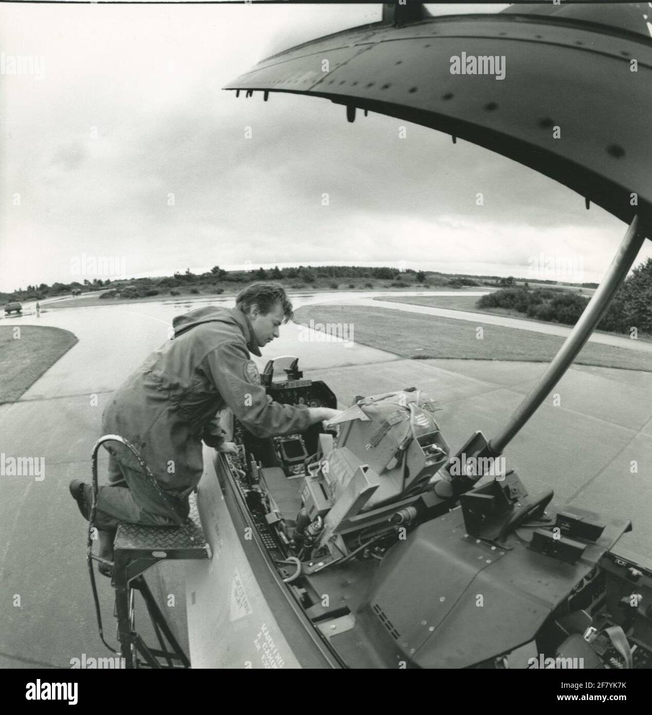 A member of the ground personnel looks into the cockpit of an F-16B two ...