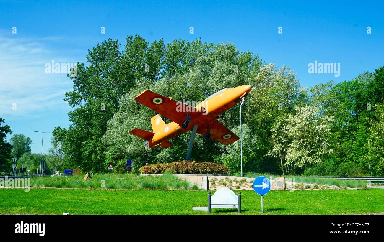 A model of fighter aircraft in the middle of road surrounded with green ...