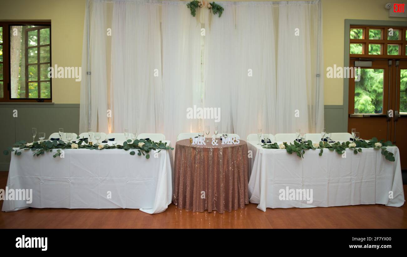 Wedding hall showing two long white tables with a round table in ...