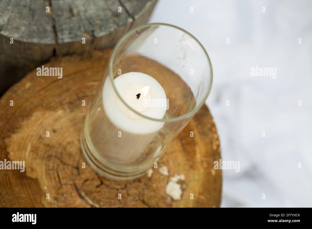 Top view closeup of a burning white candle in a glass container on a ...
