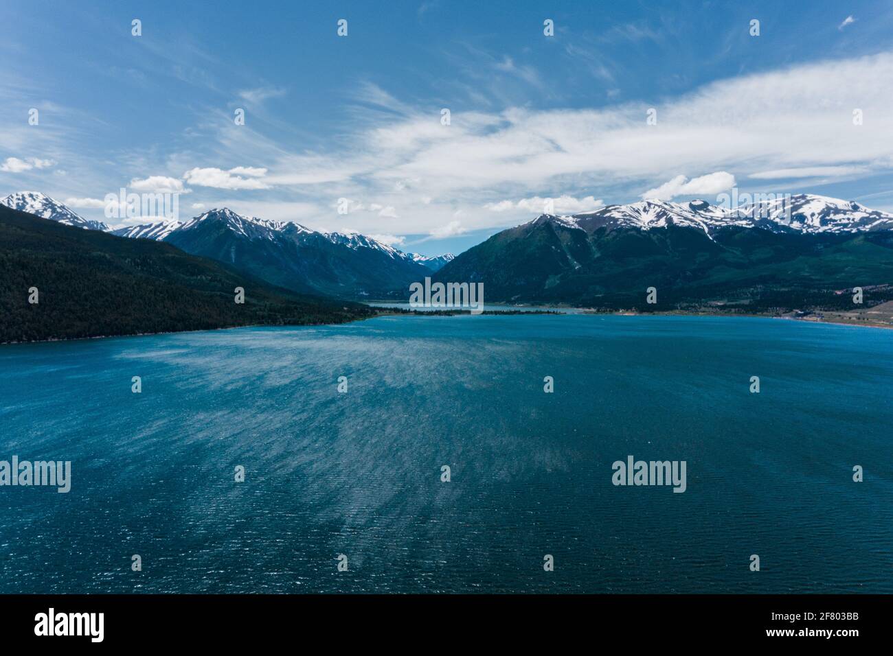 Mesmerizing view of a snow-covered mountain with a blue sky and ocean ...