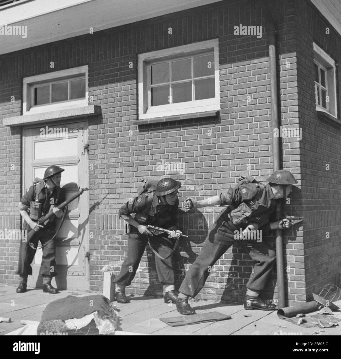 Three armed infantrylists in military terrain. The rightmost man is ...