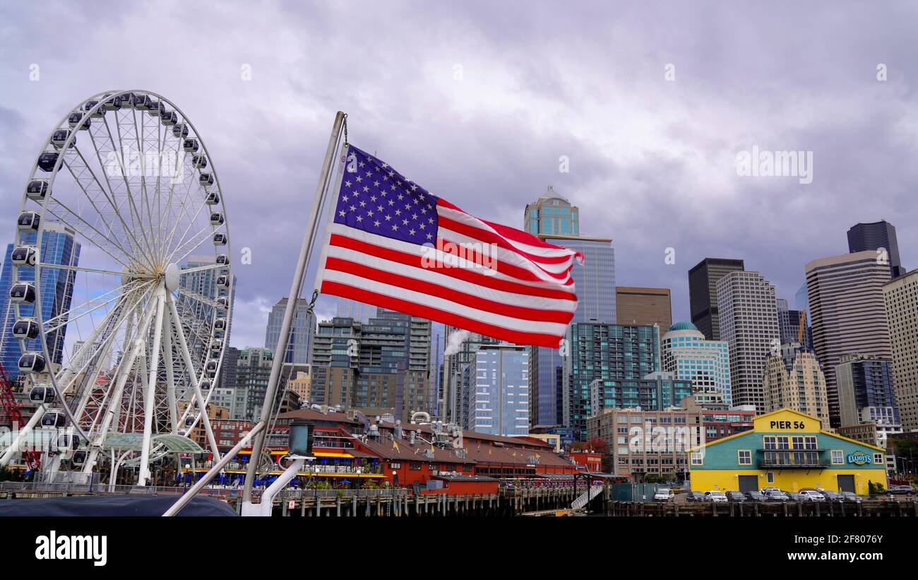 US flag flying in front of The Great Wheel at Pier 57 of Seattle ...