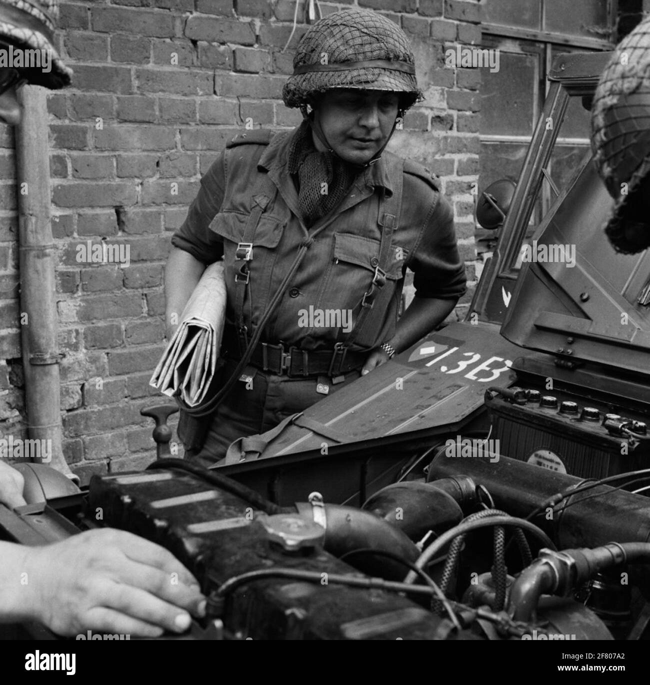 Three soldiers of the royal army inspect the engine compartment of a ...