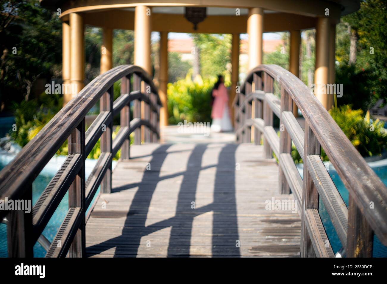 locked shot of arched wooden bridge with swimming pool on both sides ...