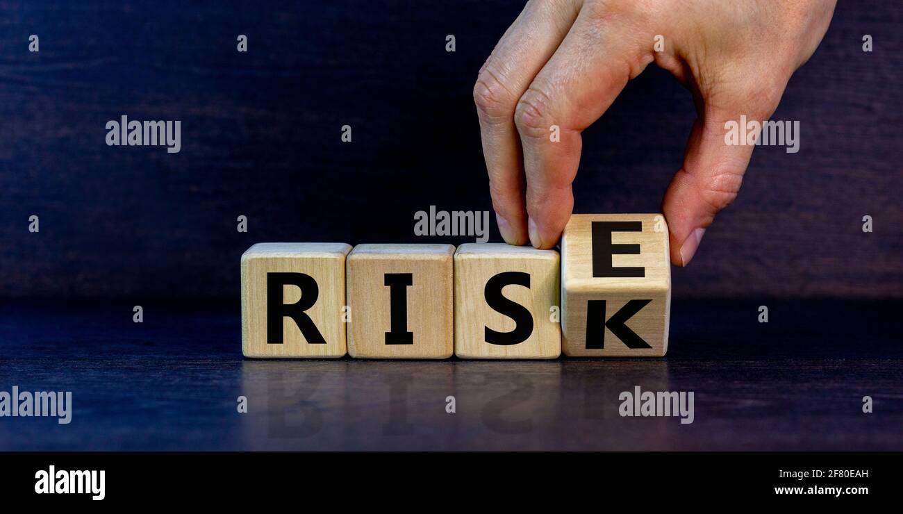 Risk vs rise symbol. Businessman turns a wooden cube and changes the ...
