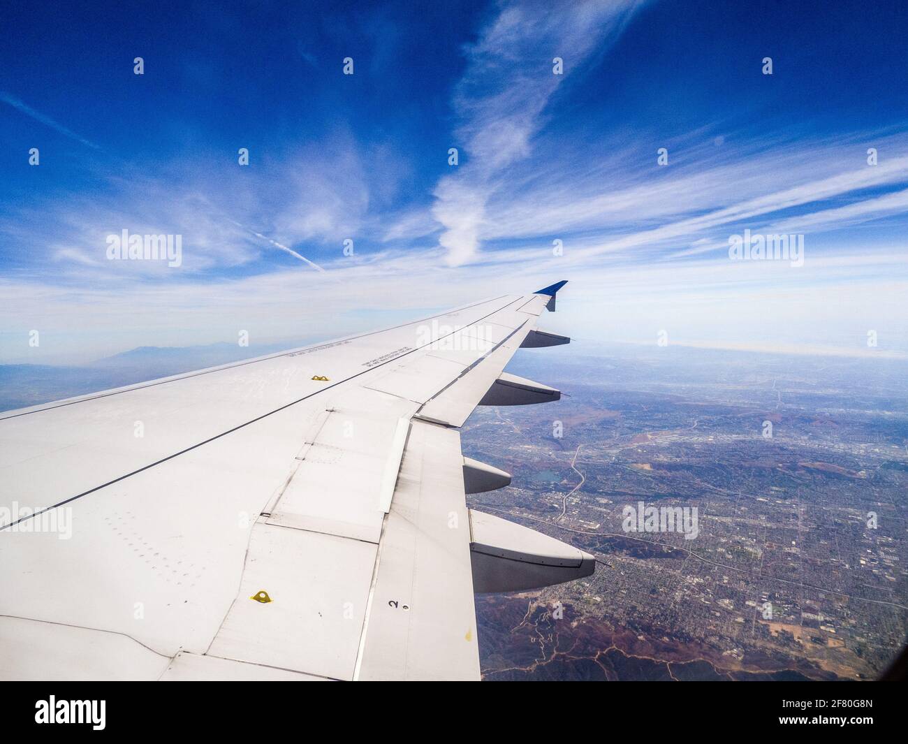 white airplane wing with blue sky and ground below Stock Photo - Alamy