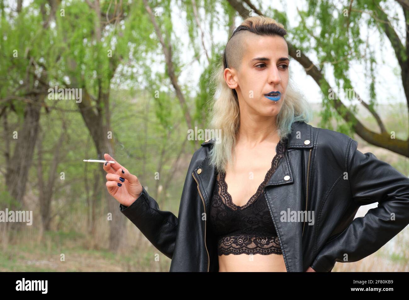 Young punk woman smoking a cigarette in a park. Rock and roll lifestyle ...