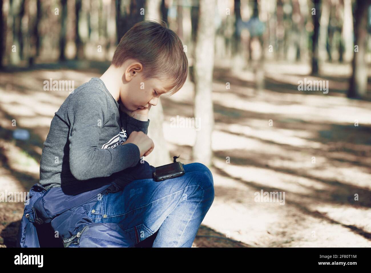 Focused boy using smartphone in park. Serious concentrated school aged ...