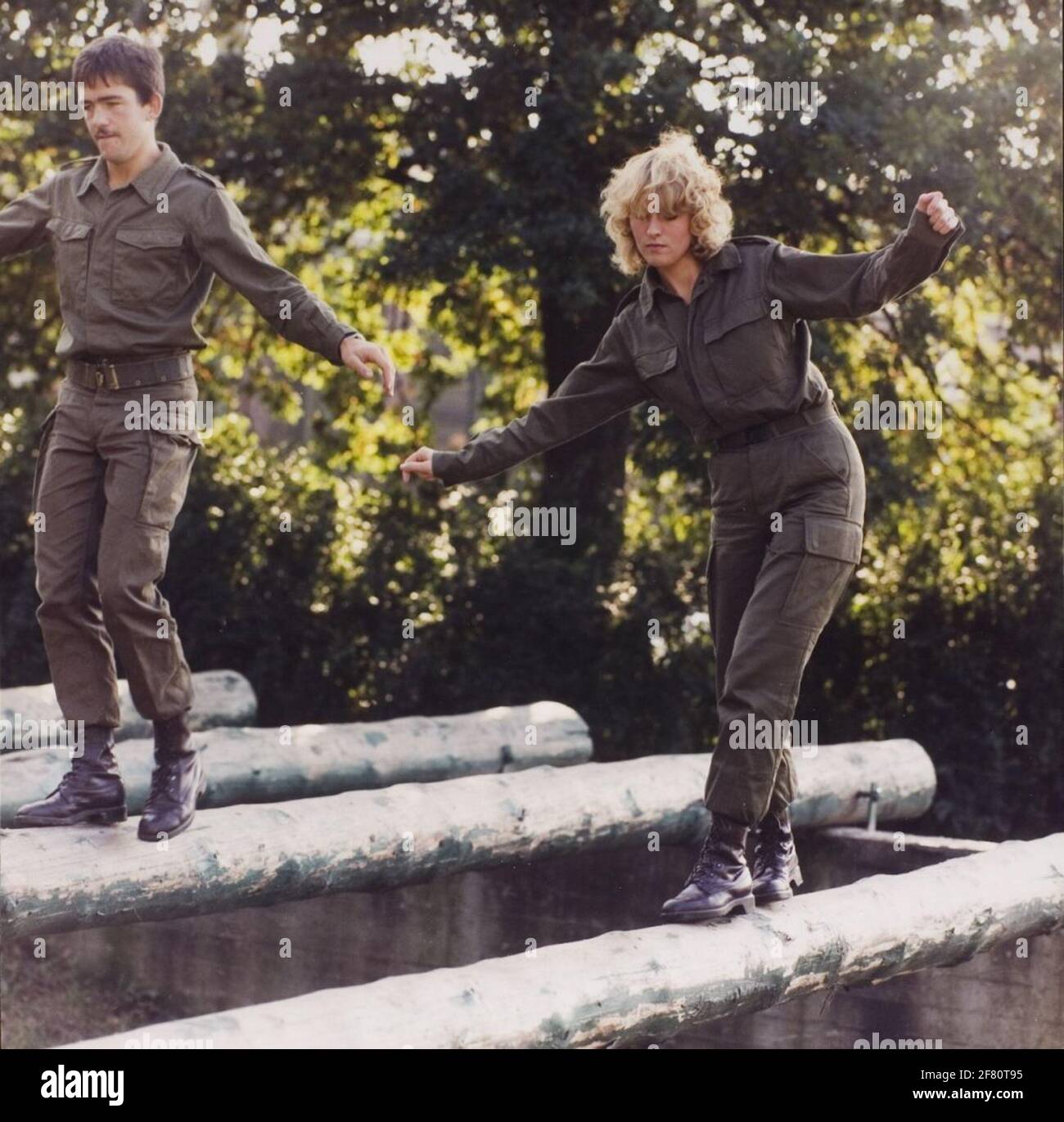 Two soldiers (man and woman) on the balance beam on the obstacle course ...