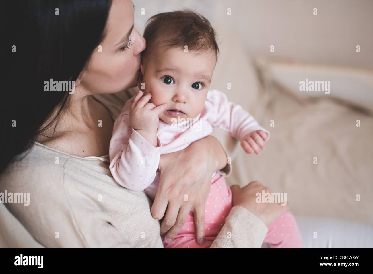 Mother holding baby girl at home. Newborn child on woman hands indoors. Motherhood. Maternity ...