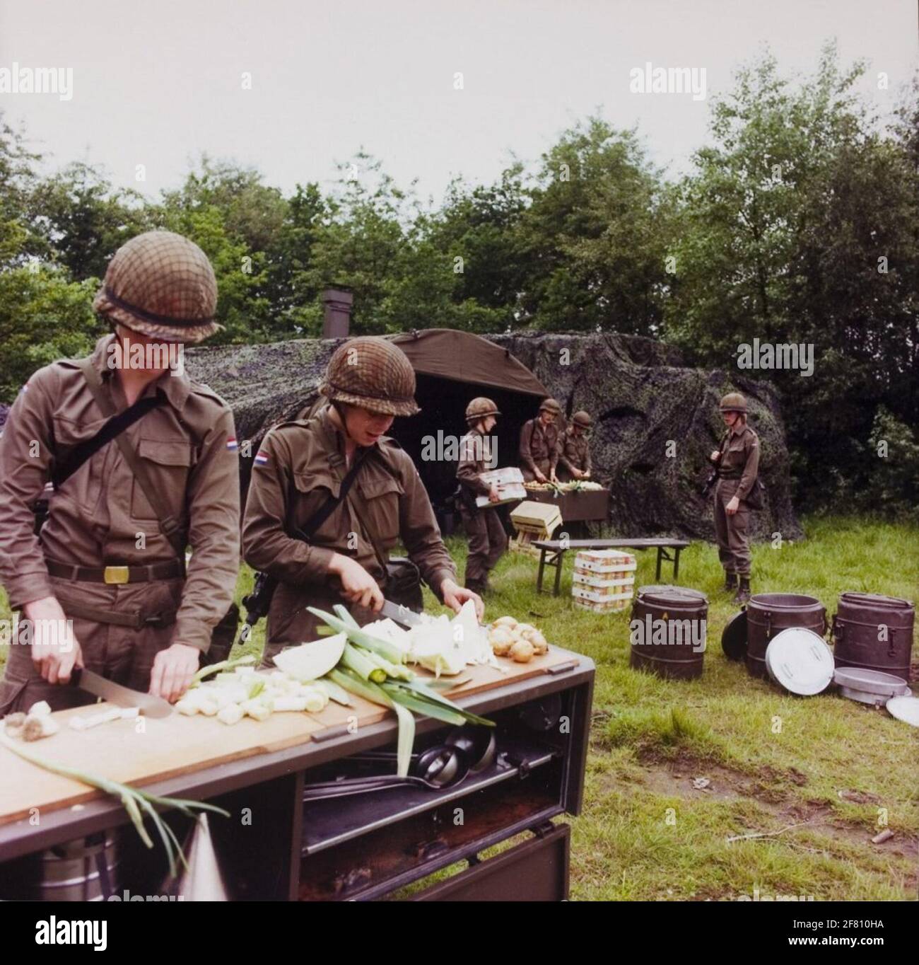 Soldiers busy cutting vegetables. In the background there is a ...