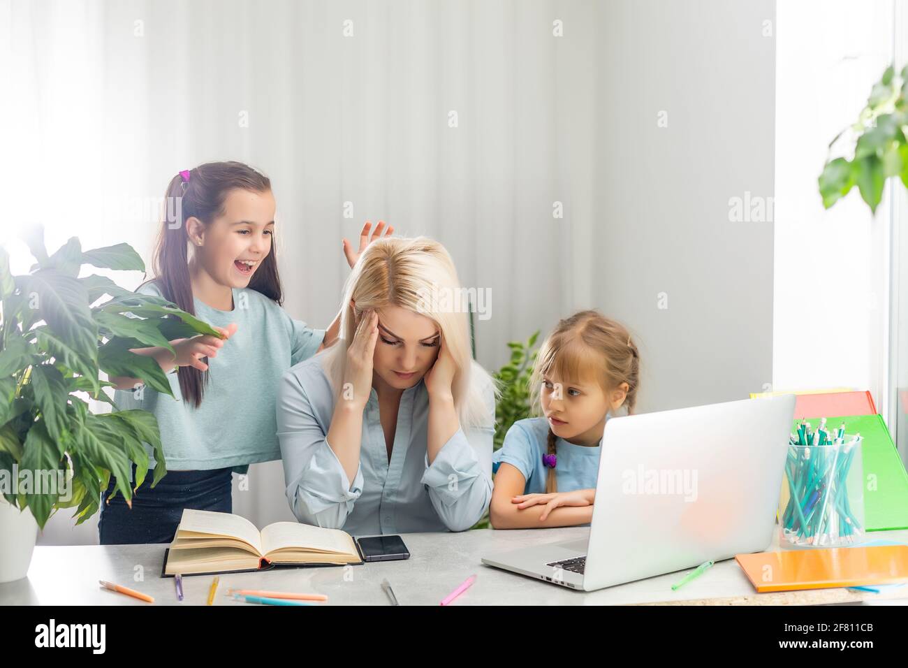 Tired mother. 2 children playing at home, exhausted stressed mother ...