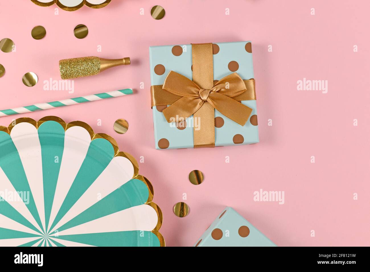 Party flat lay with teal blue paper plates, gift box, small golden ...