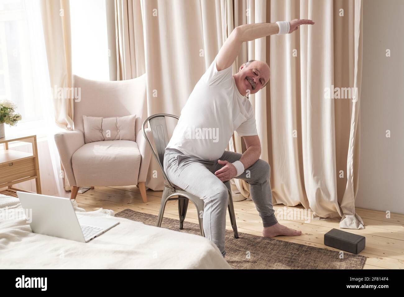 Senior caucasian man stretching side sitting on chair at his living ...