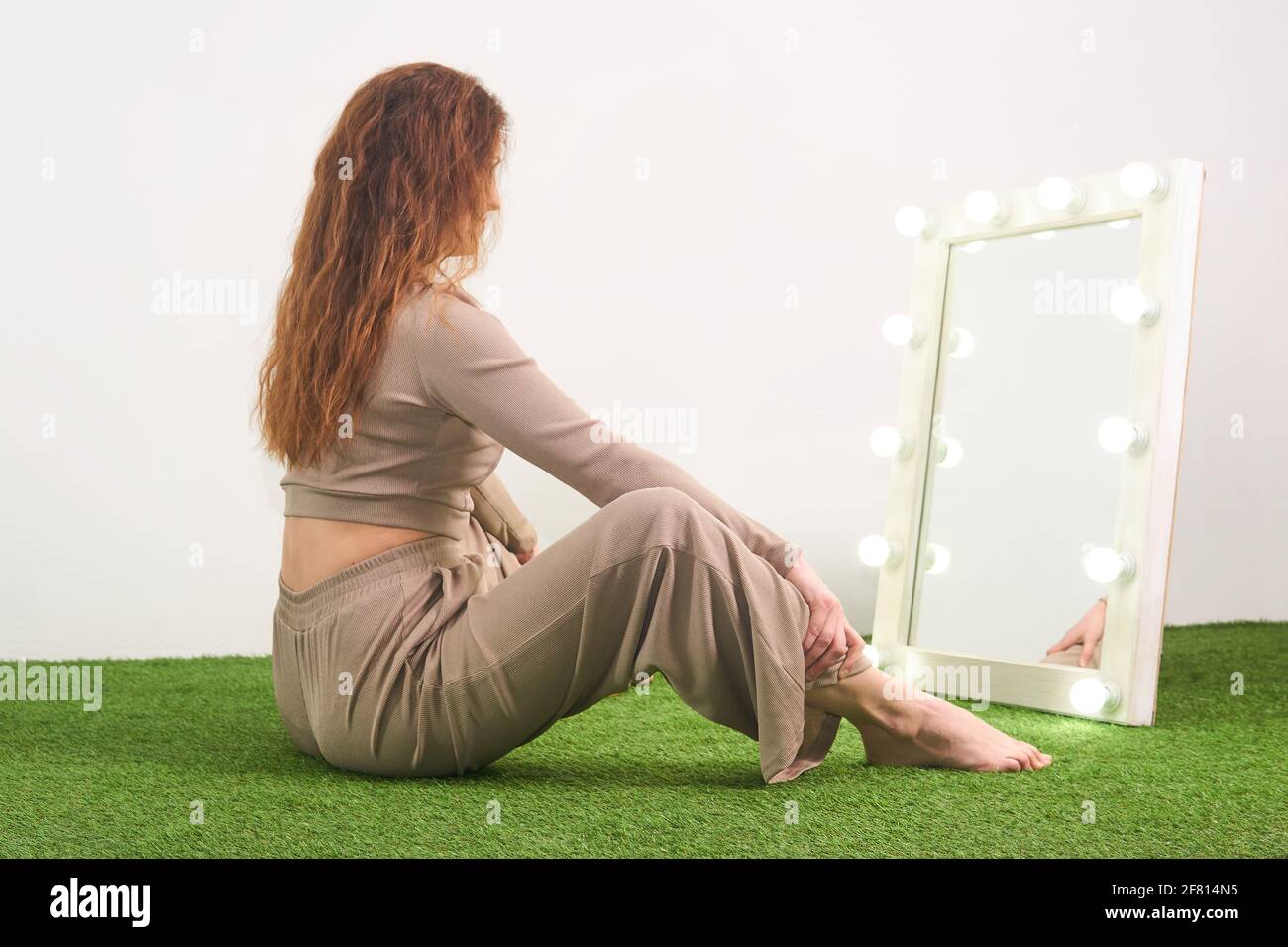 woman looking at her reflection in illuminated mirror for dressing room ...
