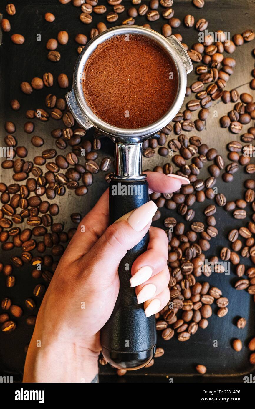 Woman's hand with beautiful nails and holding portafilter with coffee ...