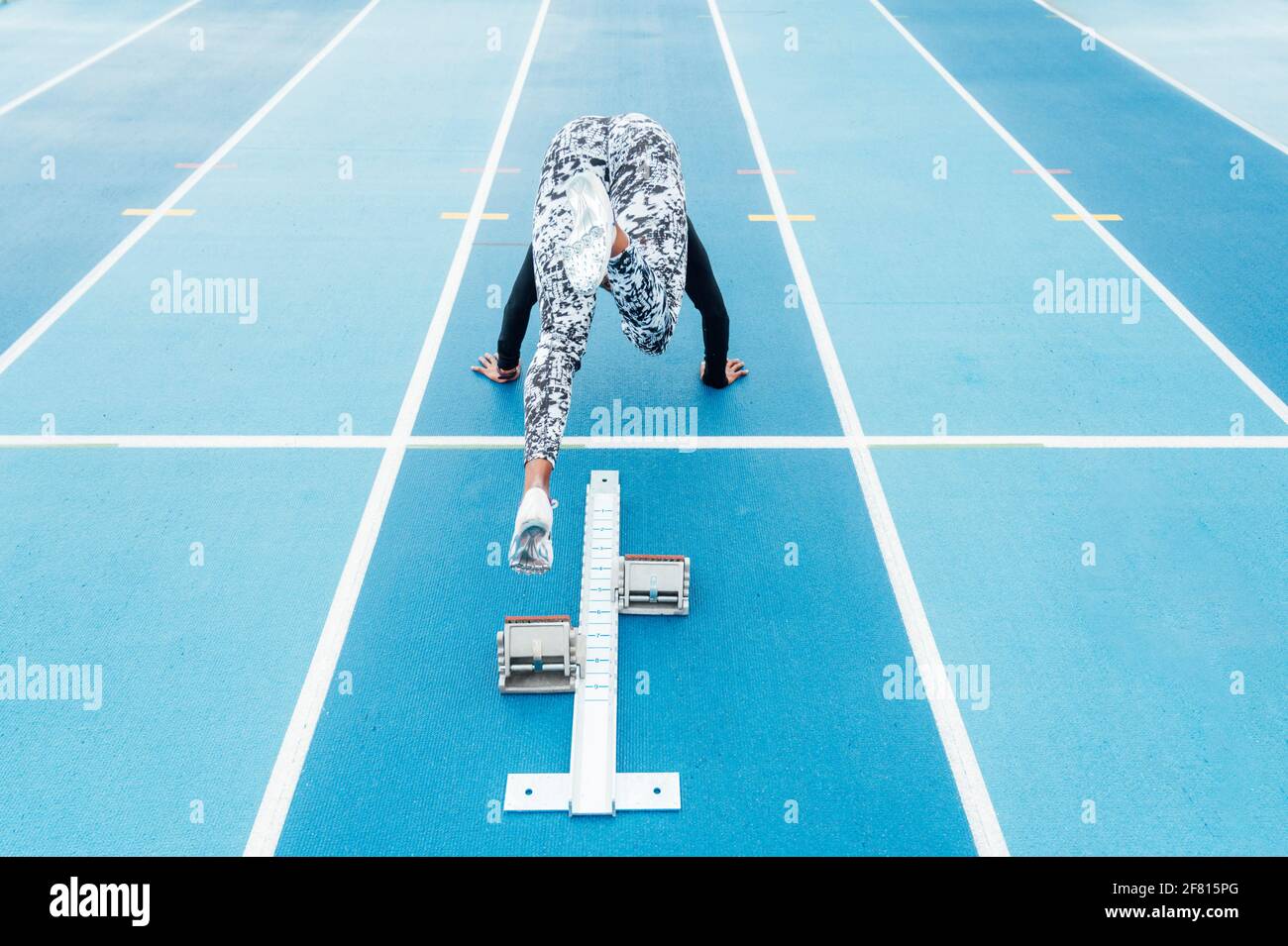 Back view of young strong sportswoman beginning to run fast from ...