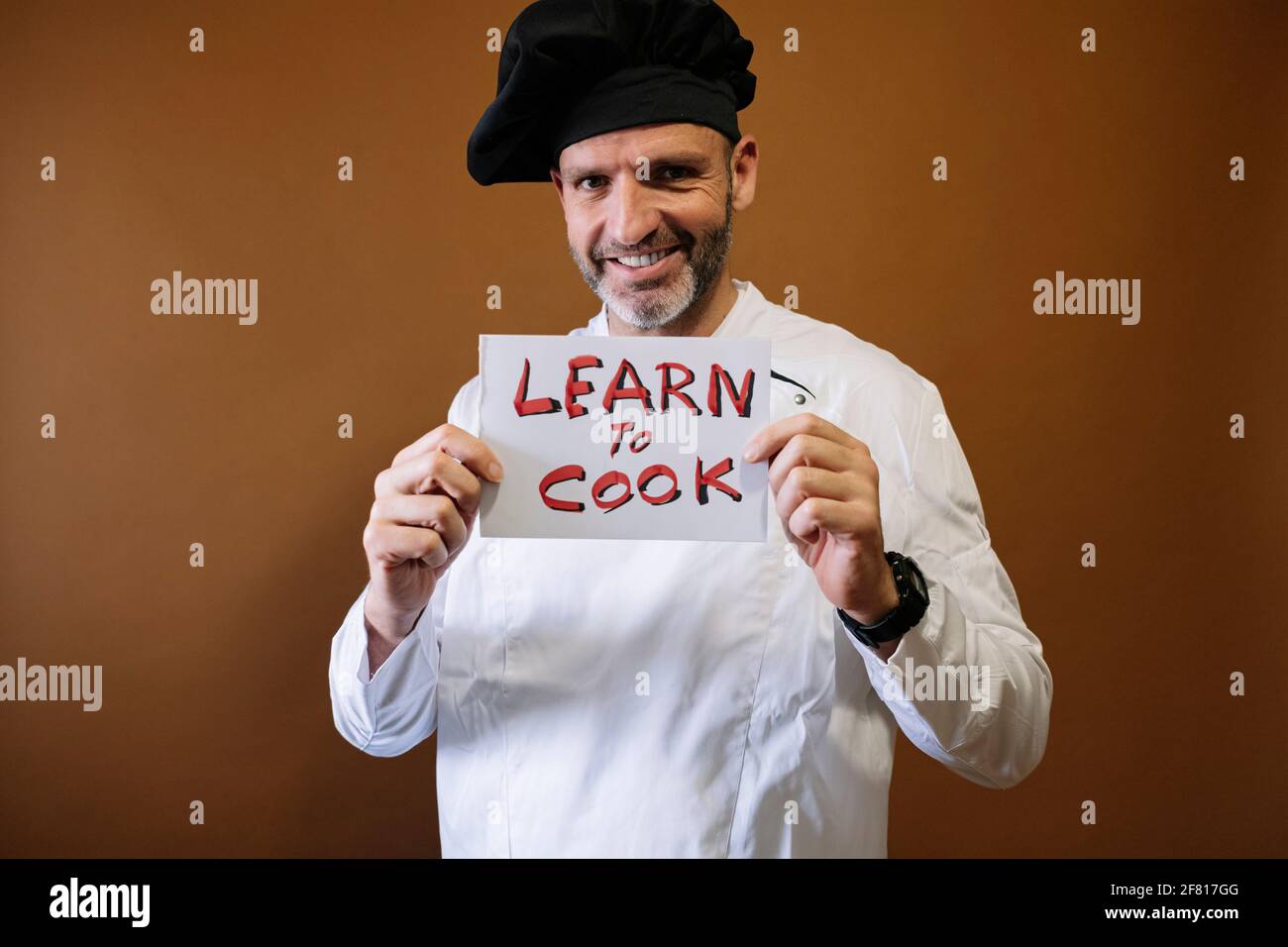 Chef man holding a sign that says learn and cook Stock Photo - Alamy