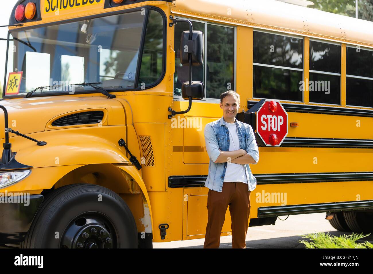 Smiling bus driver looking at camera outside the elementary school ...